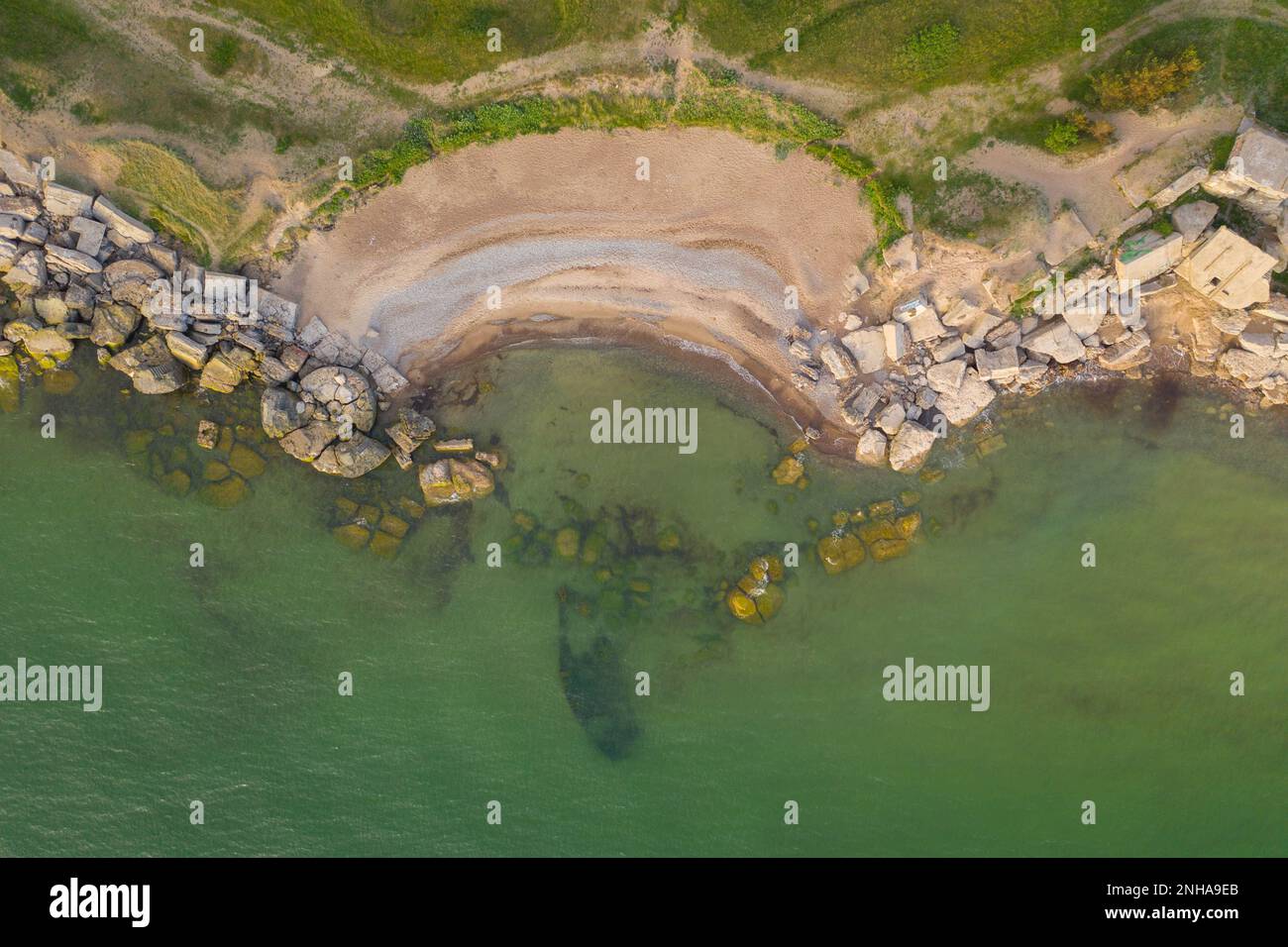 drone photography of rocky cliff and small beach during summer evening ...