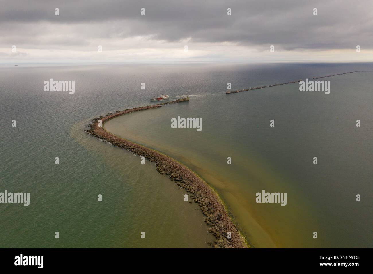 Drone photography of harbor seawall and ship sailing away during summer ...