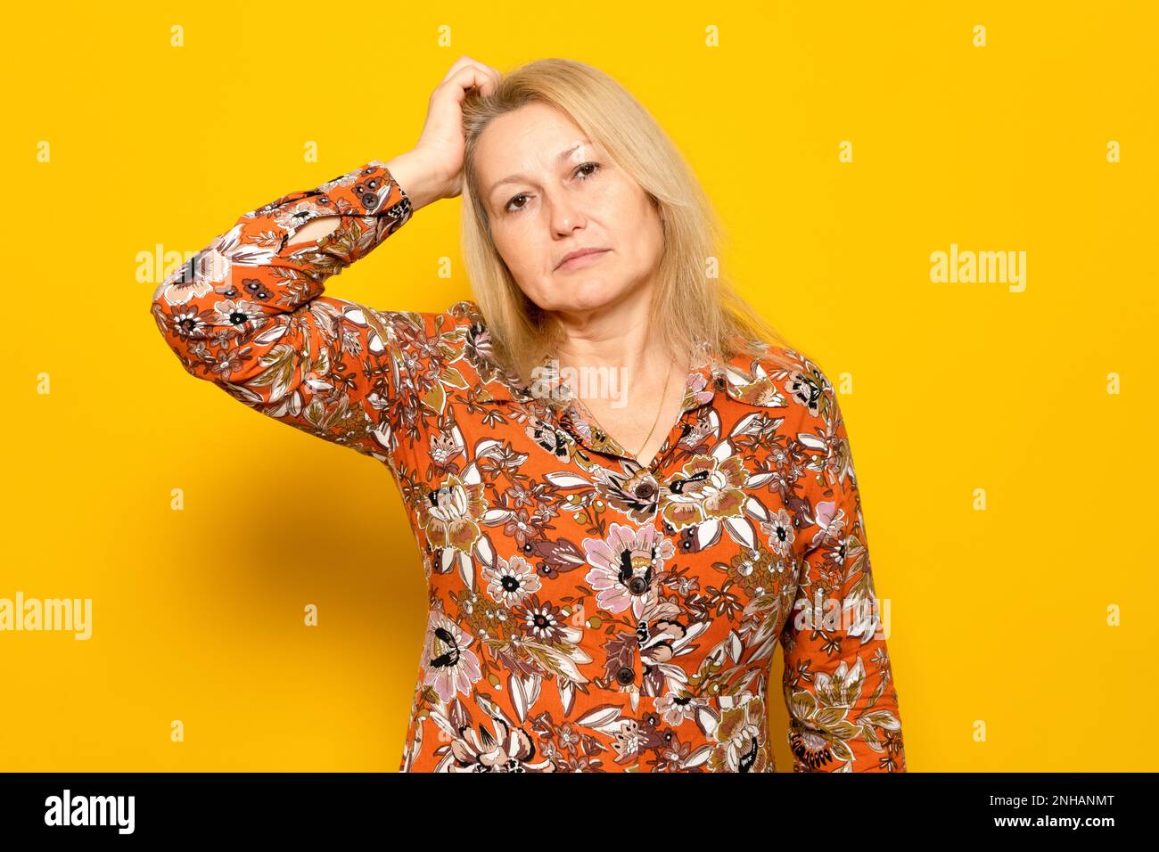 Woman scratching her head with doubts and confusion isolated on yellow ...