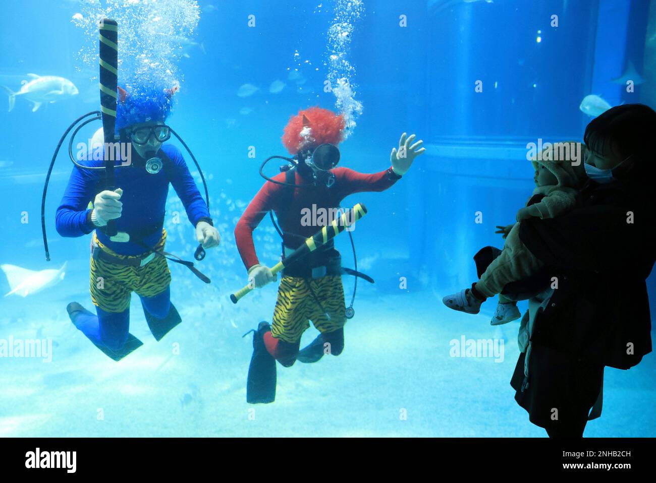 Divers wearing devil costumes welcome visitors in a giant fish tank at ...