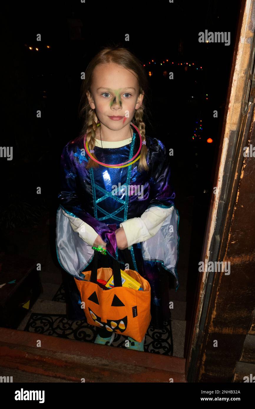 Somber girl with braids in costume out for tricks or treats with a ...