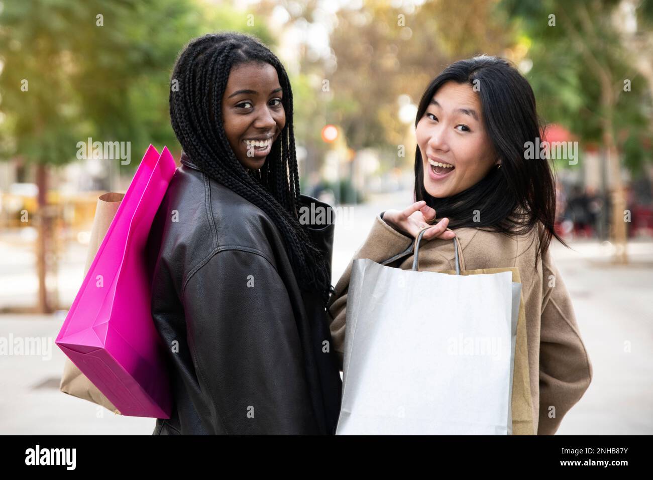 Rear view of two women walking in street for shopping - People ...