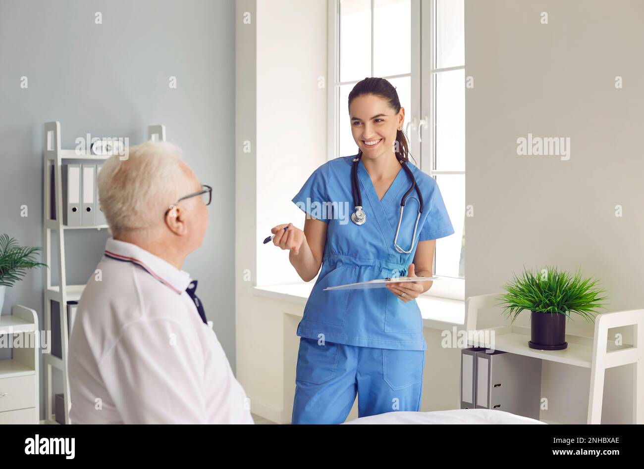 Smiling physician with clipboard interviewing senior patient during ...