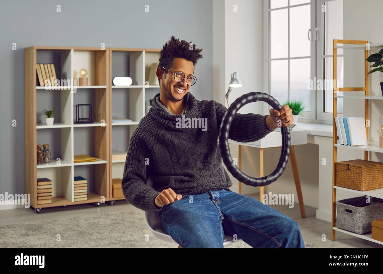 Funny, happy young African American man pretending to drive an ...
