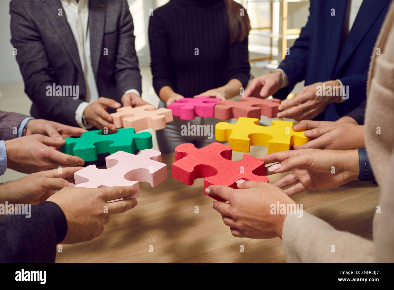 Hands of a group of business people assembling jigsaw puzzle ...
