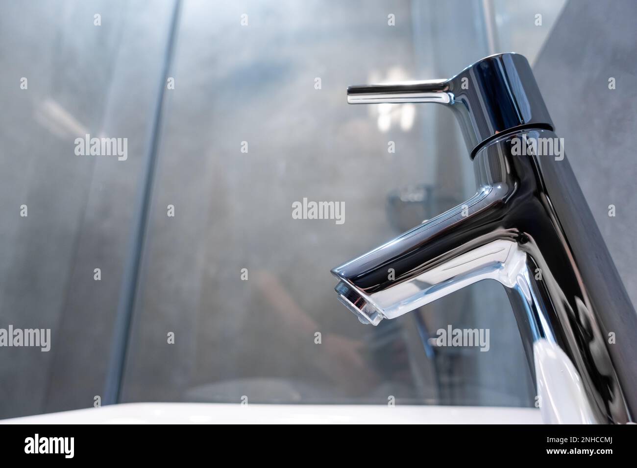 A chrome faucet in an elegant bathroom. Object photographed from below ...