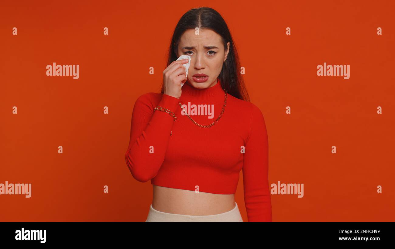 Upset disappointed pretty young woman in crop top wipes tears and cries ...