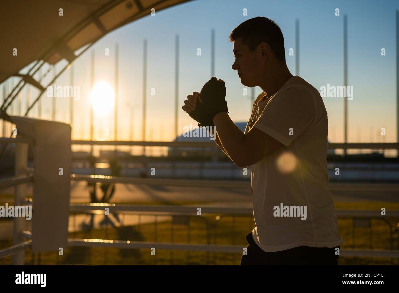 A man trains in boxing at the stadium at sunset. Athlete silhouette ...