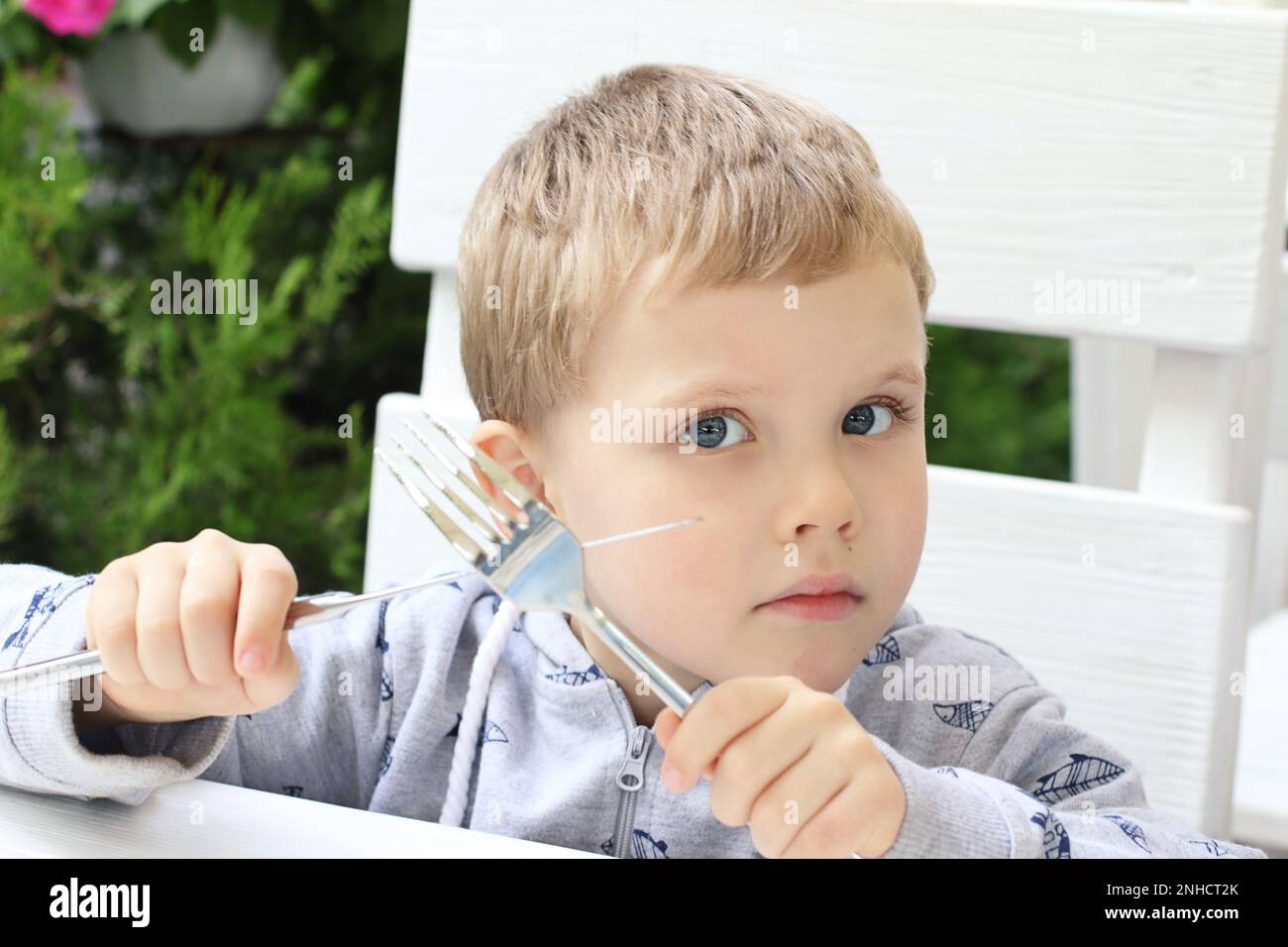 The child shows that he wants to eat. Kid holding fork and knife over ...