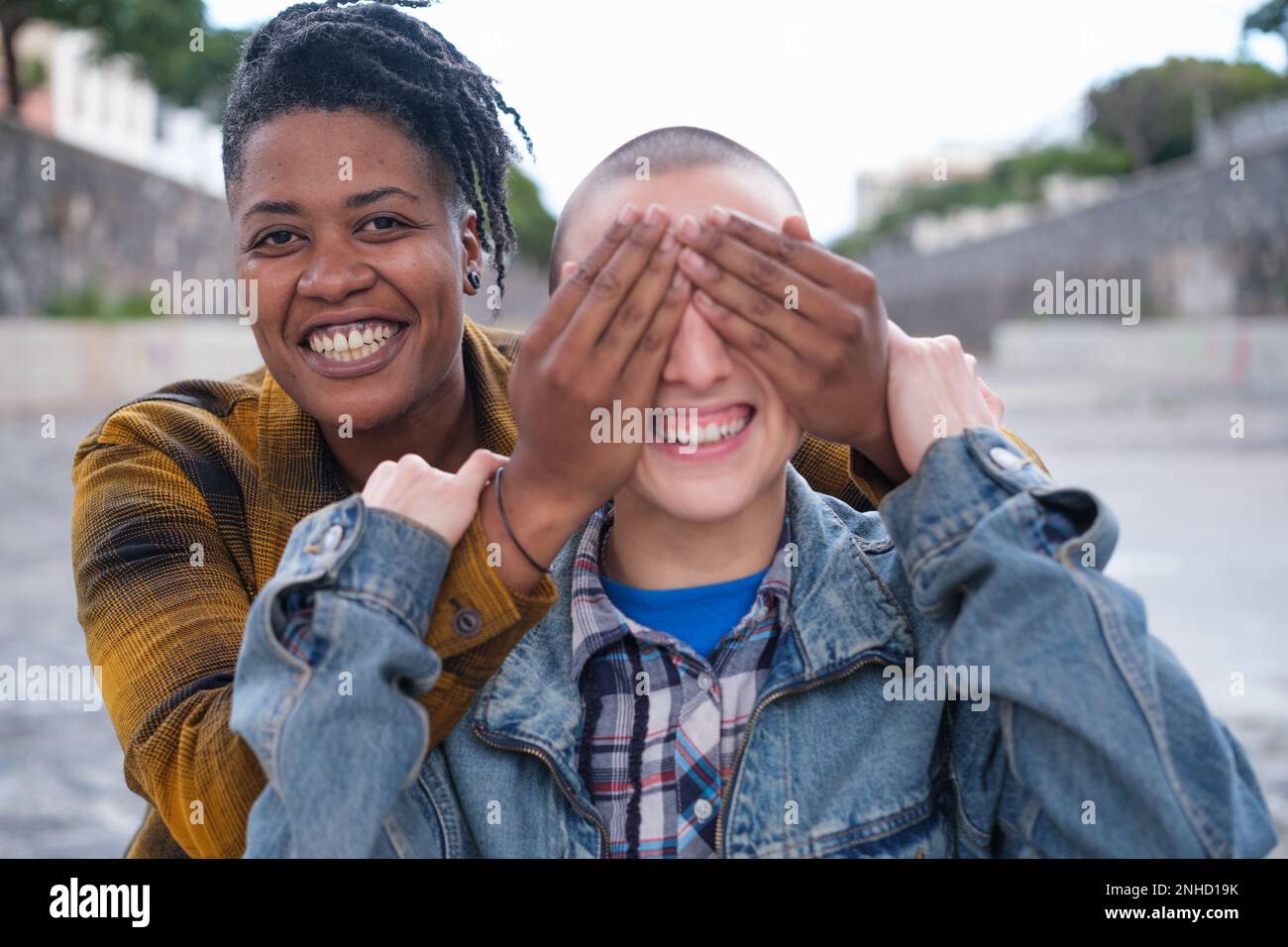 One Friend surprising the other and covering her eyes with her hands ...