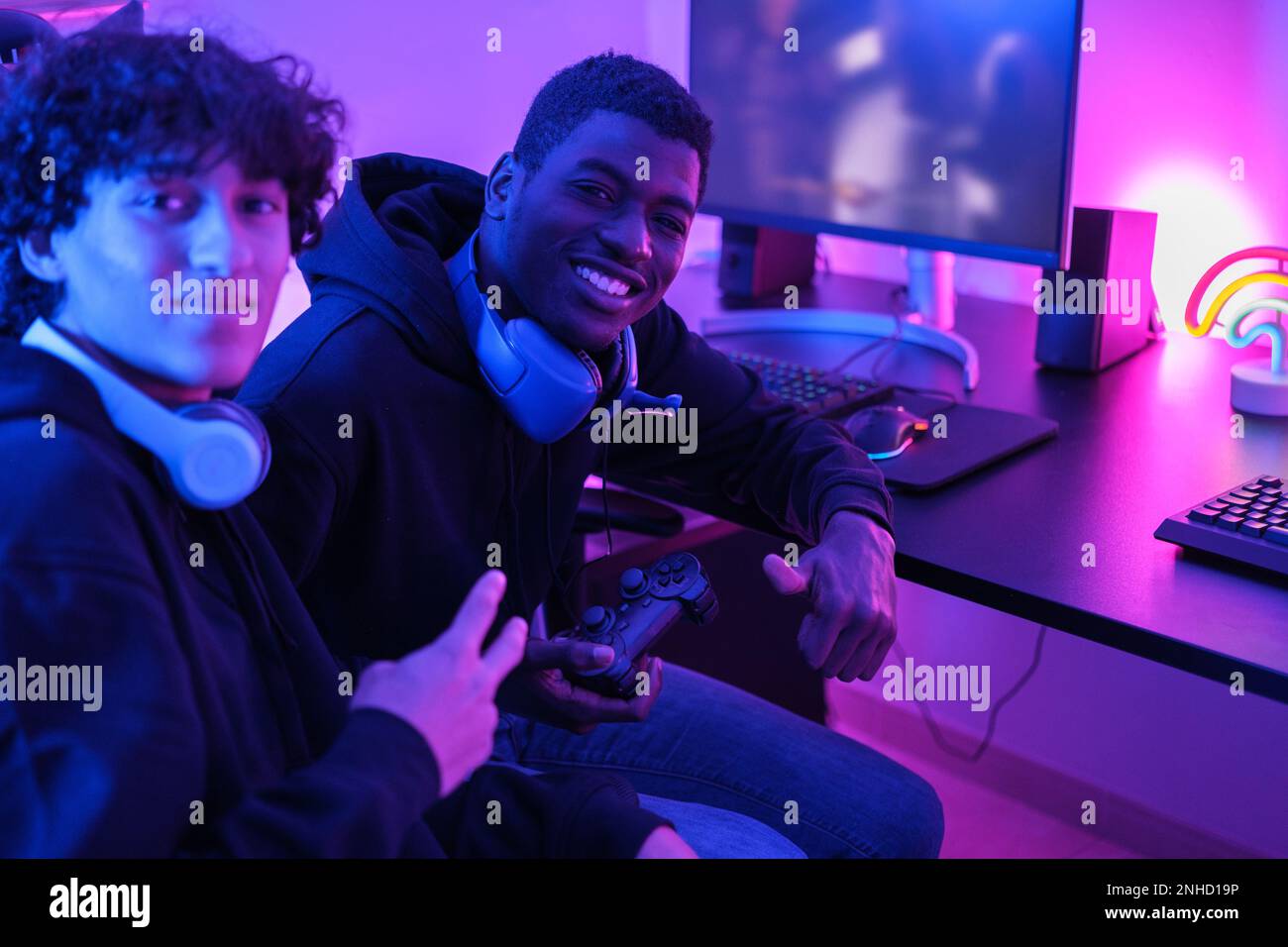 Two gamer friends together playing video games as a team and posing for ...