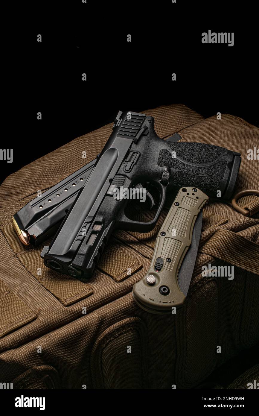 A pistol, cartridges for it and a folding knife on a brown backpack ...