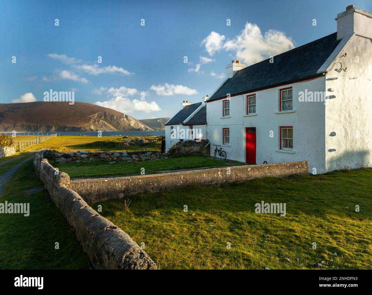 White farm house with red door beside the beach on Achill island on the ...