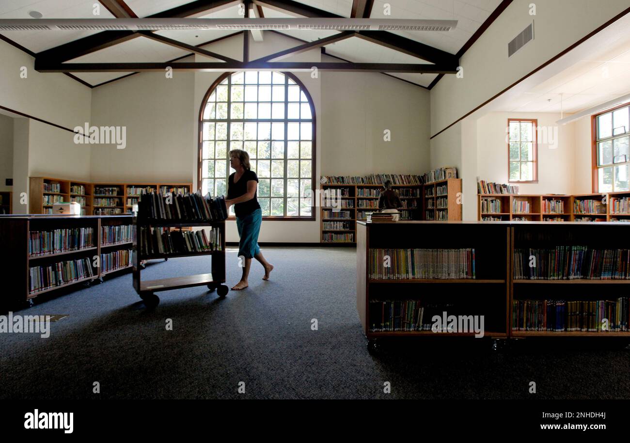 Teacher-Librarian, Laura Remer, stocks books inside the new library, at ...