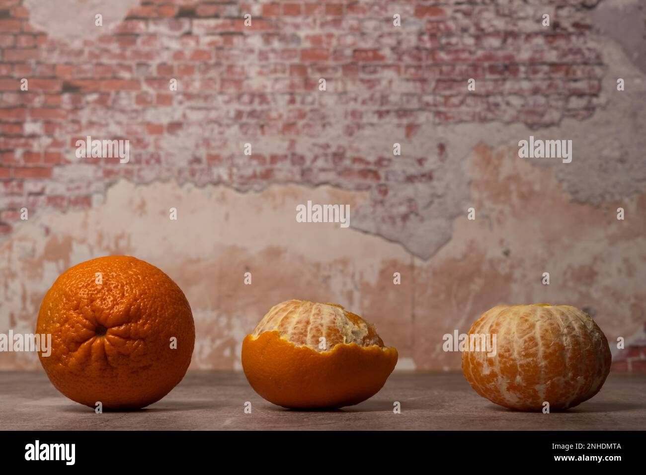 Three mandarins, whole, half peeled and peeled on a wooden table with a ...