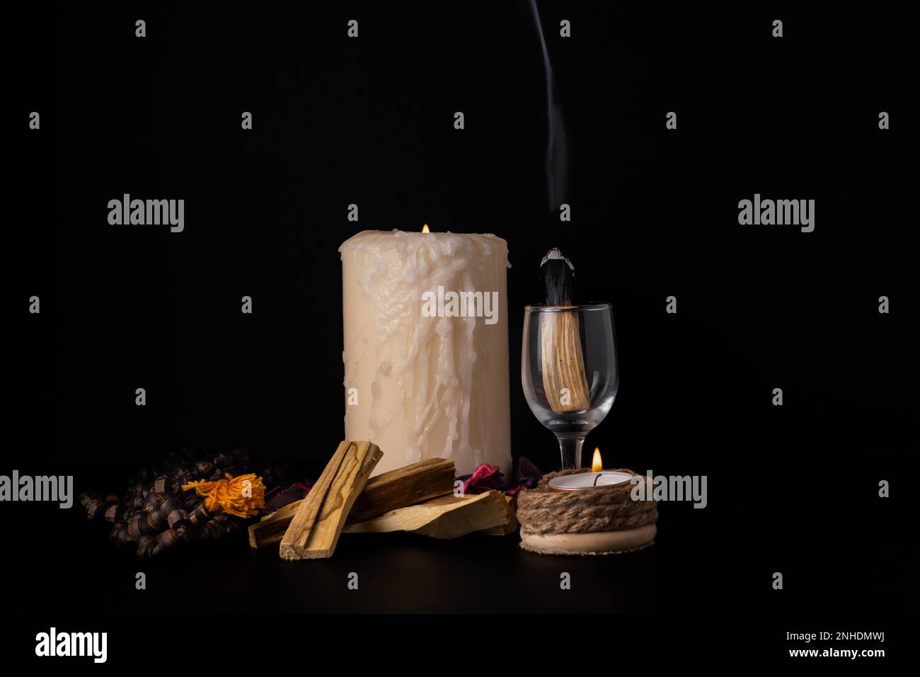 Palo santo, holy stick smoking in a glass cup with lighted candles and ...