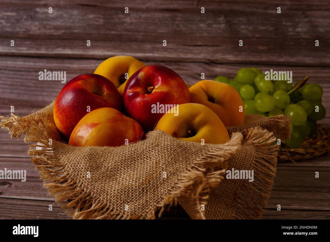 Group of fresh nectarines on a raffia cloth with a dark wood background ...