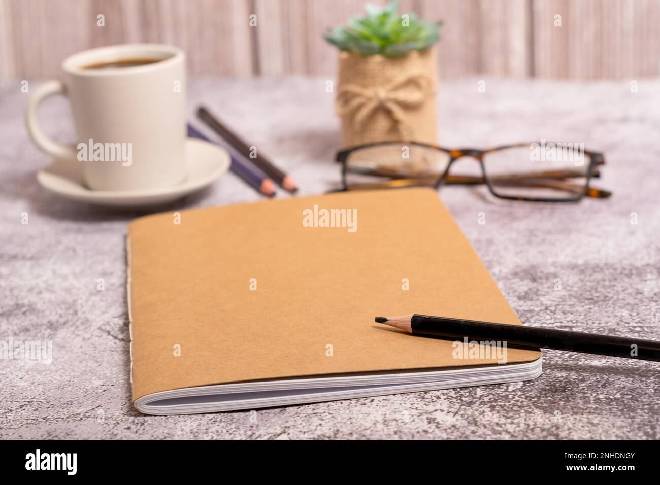 Closed notebook with brown covers, pencil, glasses and coffee cup with ...