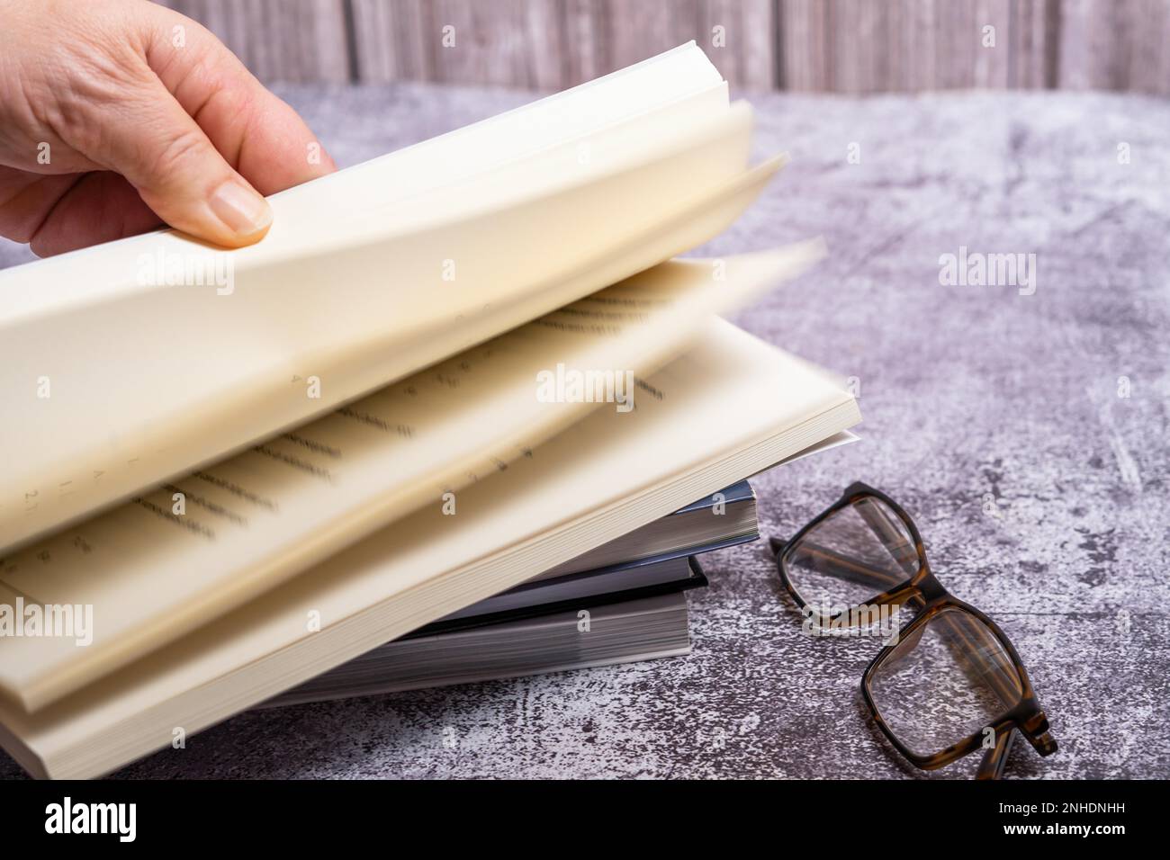 Womans hand turning the pages of a book with an out-of-focus background ...