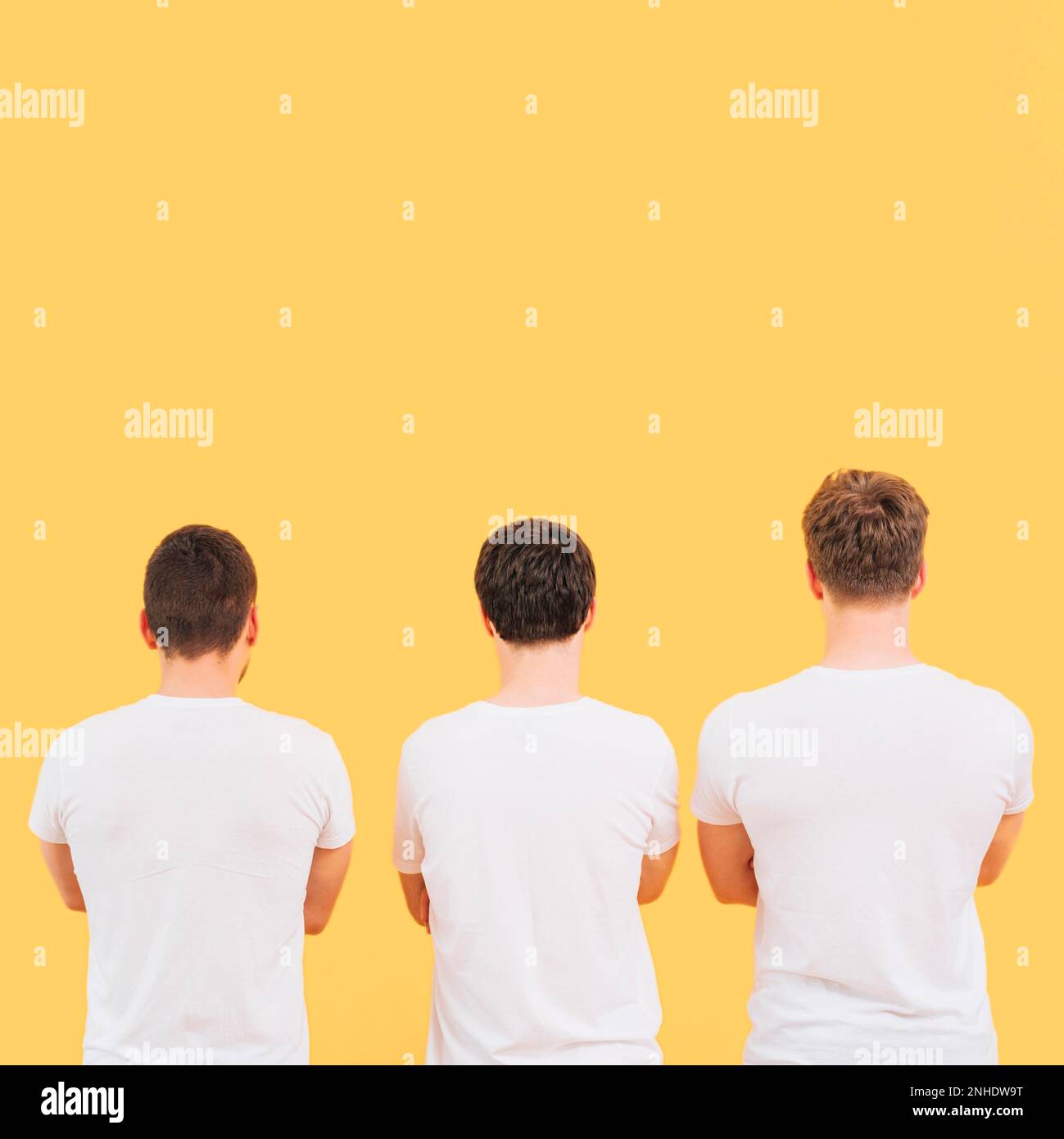 rear view men white t shirt standing against yellow background. High ...