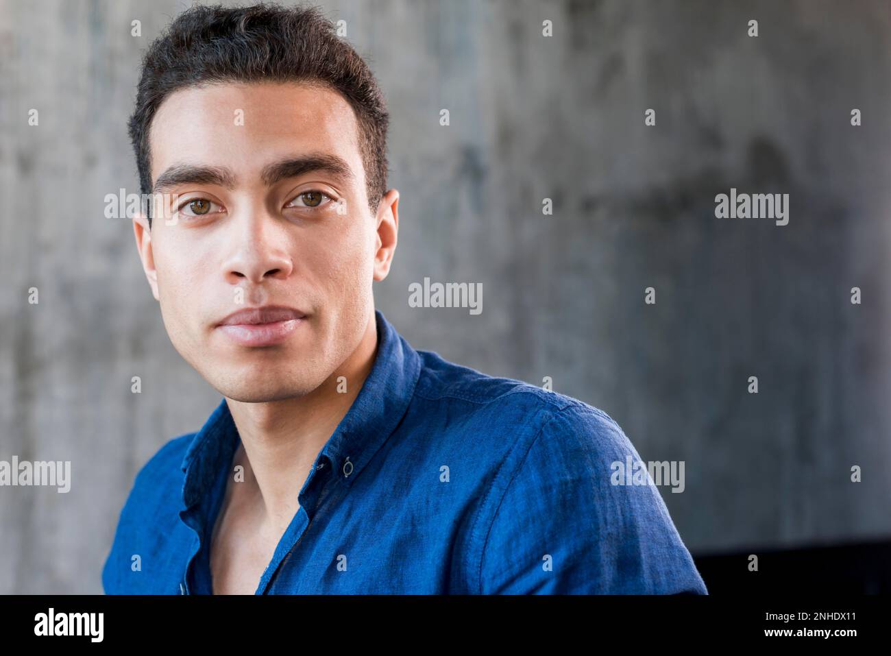 close up young man looking camera against grey wall Stock Photo - Alamy