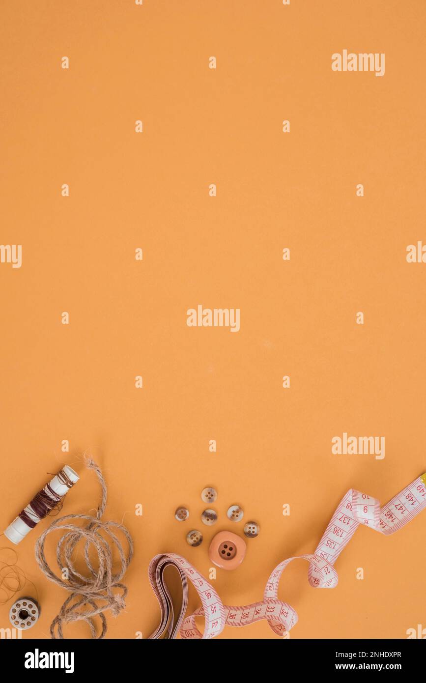 Spool jute string button measuring tape orange background Stock Photo ...