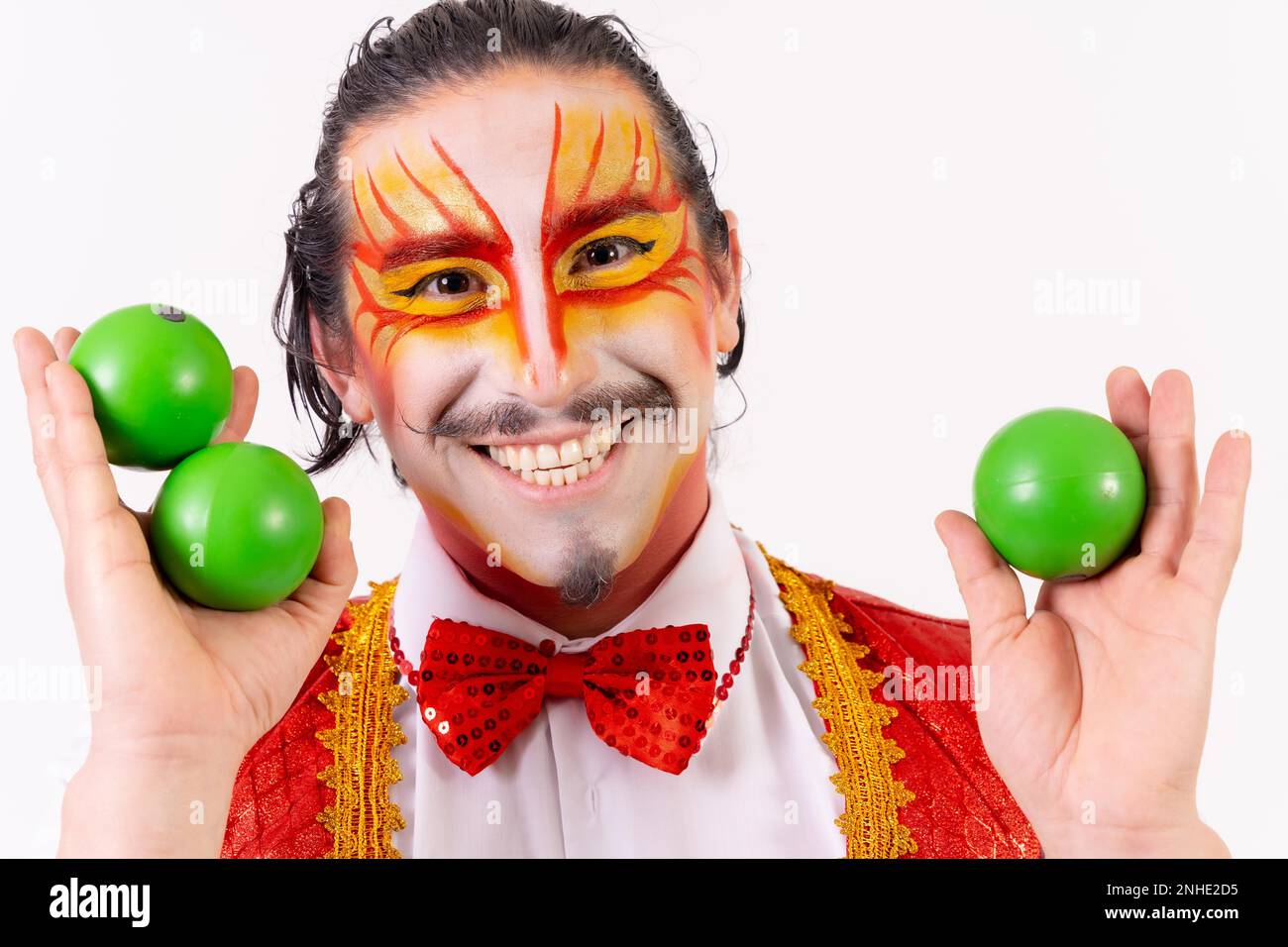 Portrait of smiling juggler juggling green balls isolated on white ...