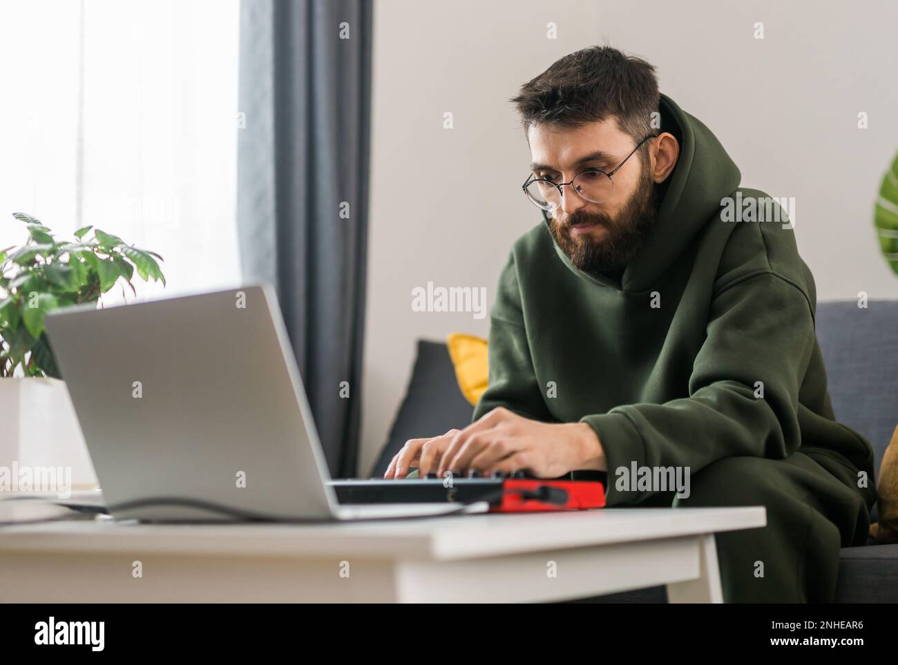 Man recording electronic music track with portable midi keyboard on ...