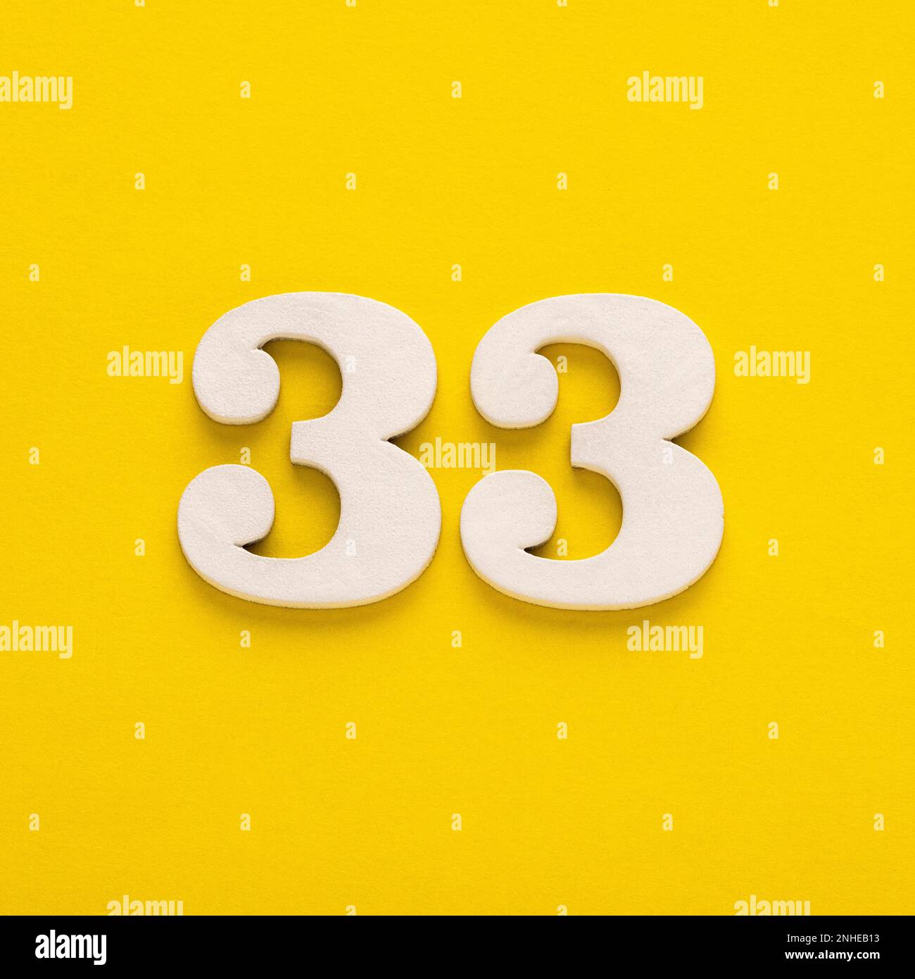 Number 33 - Two figures in white on a yellow background Stock Photo - Alamy