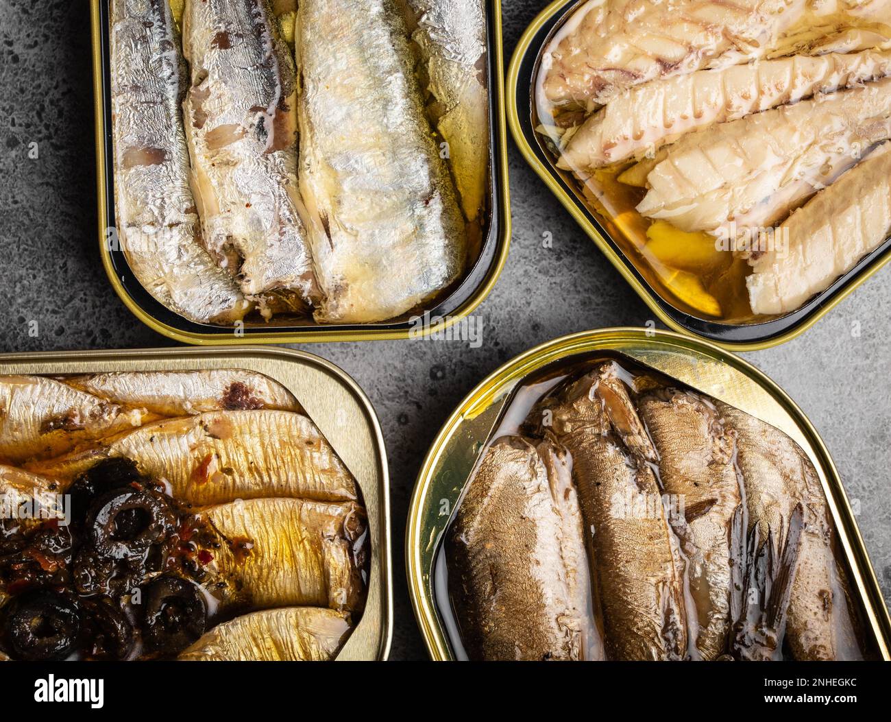 Assorted canned fish in a tin over gray concrete background: sardine ...