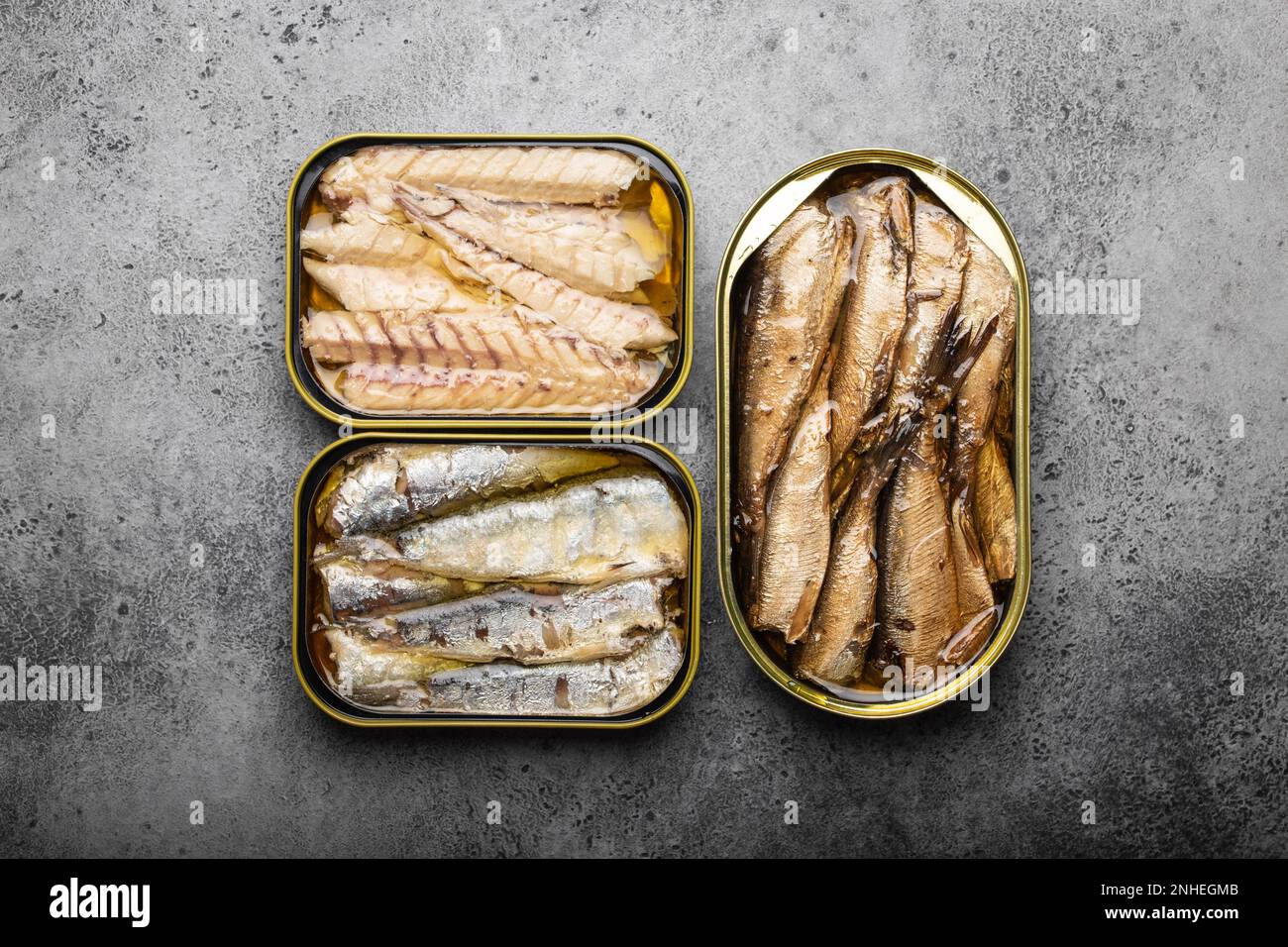 Assorted canned fish in a tin over gray concrete background: sardine ...