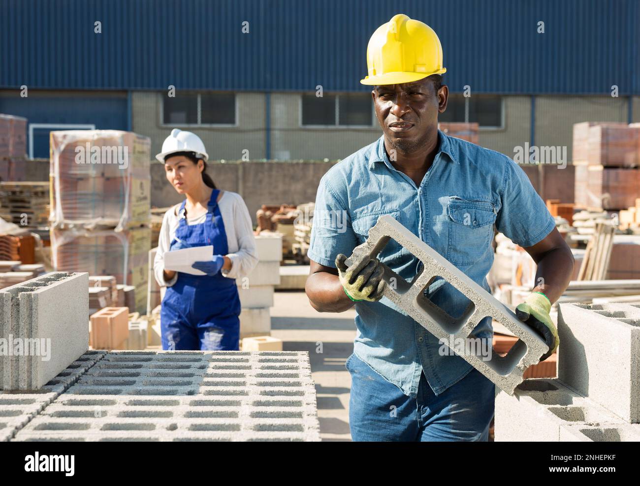 man is checking quality of bricks in the open area of a construction ...
