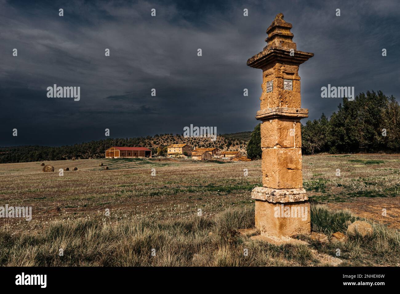old Milestone at the edge of a field against rain clouds in the ...