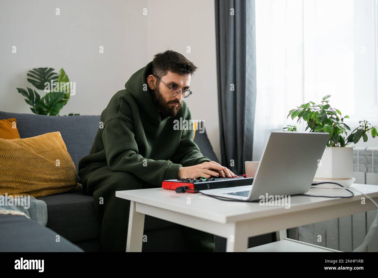 Man recording electronic music track with portable midi keyboard on ...