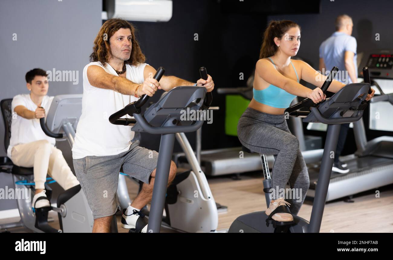 Group of people working out on stationary bicycle in gym Stock Photo ...