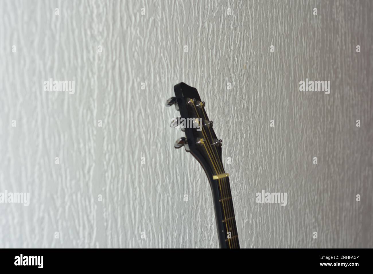 Acoustic guitar neck lean on the white wall Stock Photo - Alamy