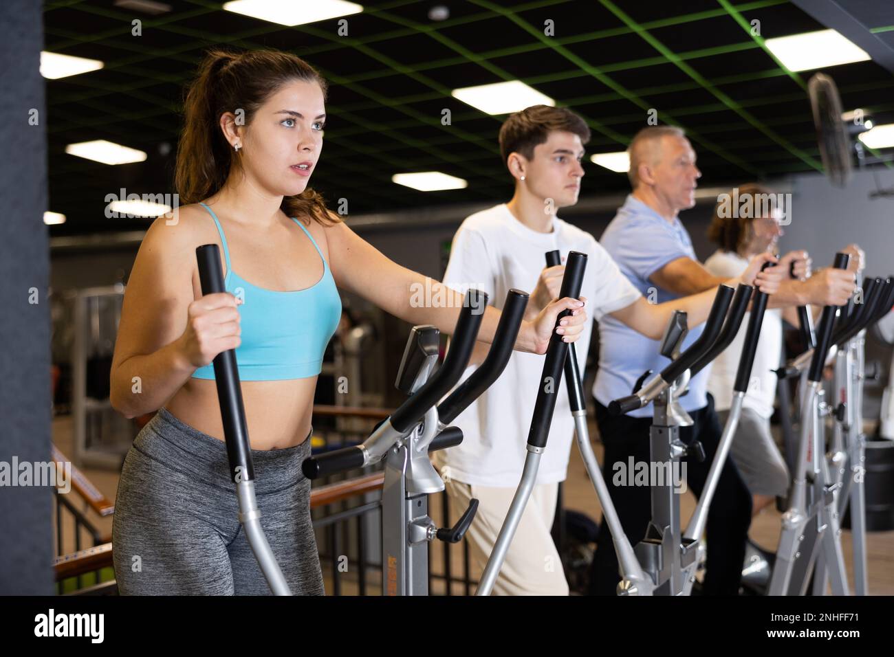 Race walking on elliptical trainers in modern gym Stock Photo - Alamy