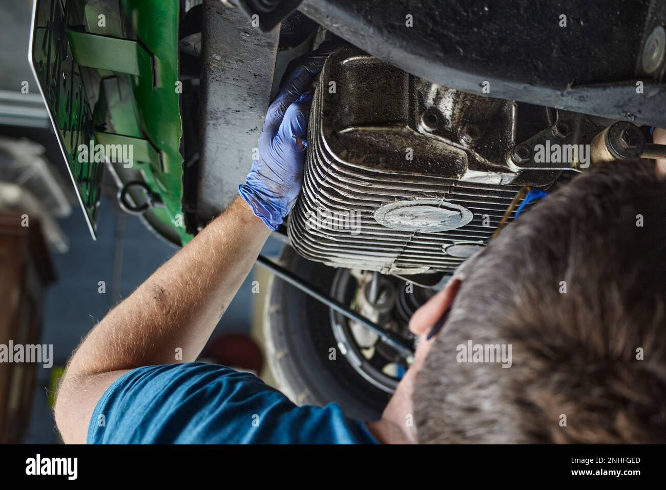 This mechanic man is repairing a green Mini Cooper in his garage, under ...