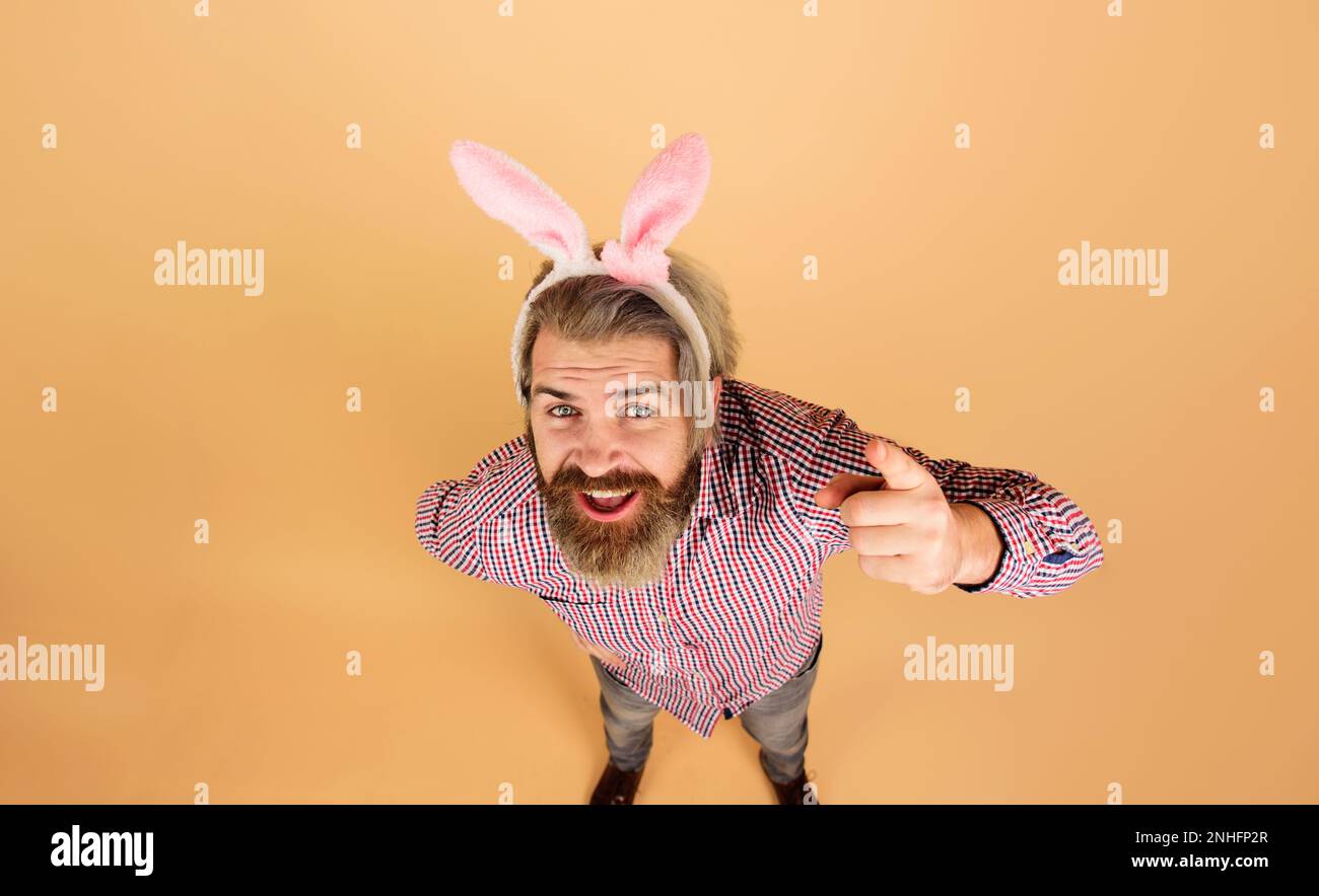 Easter man. Bearded man in bunny ears pointing finger up. Rabbit man on ...