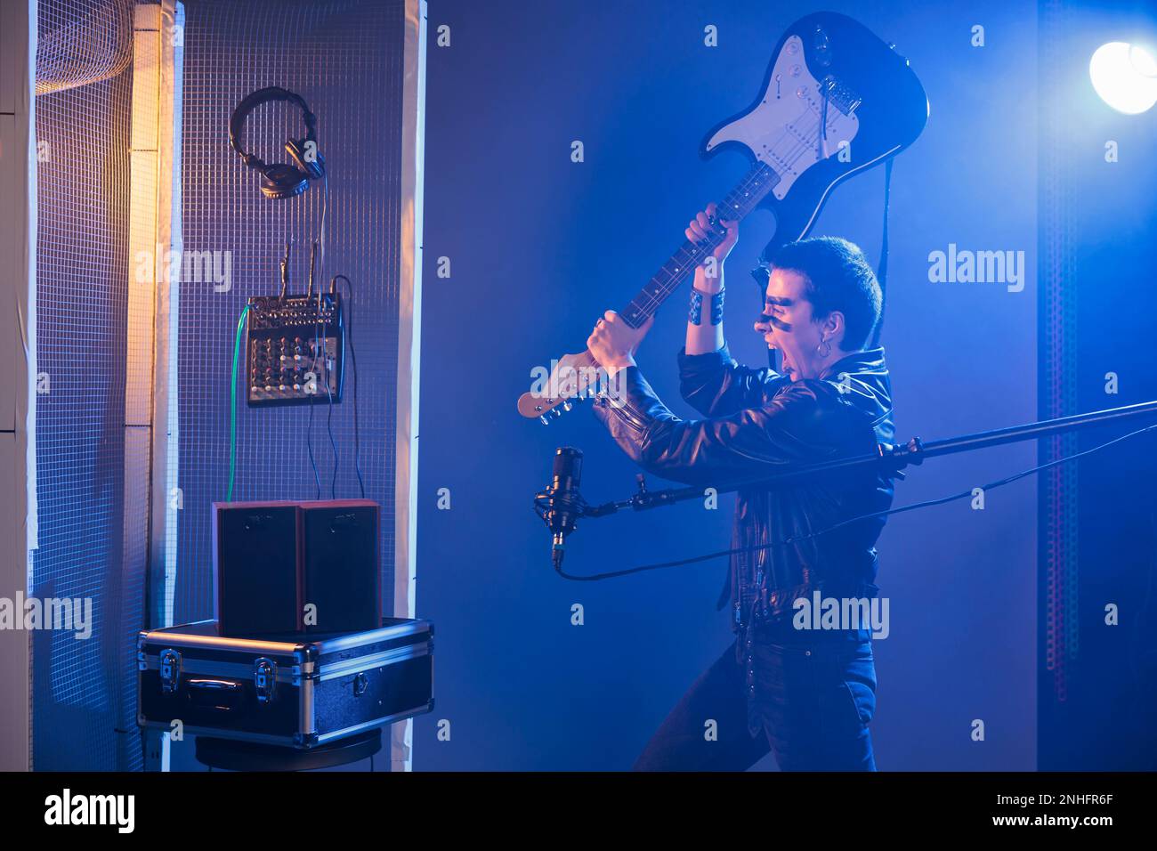 Crazy funky rocker throwing guitar in studio, wearing leather jacket ...
