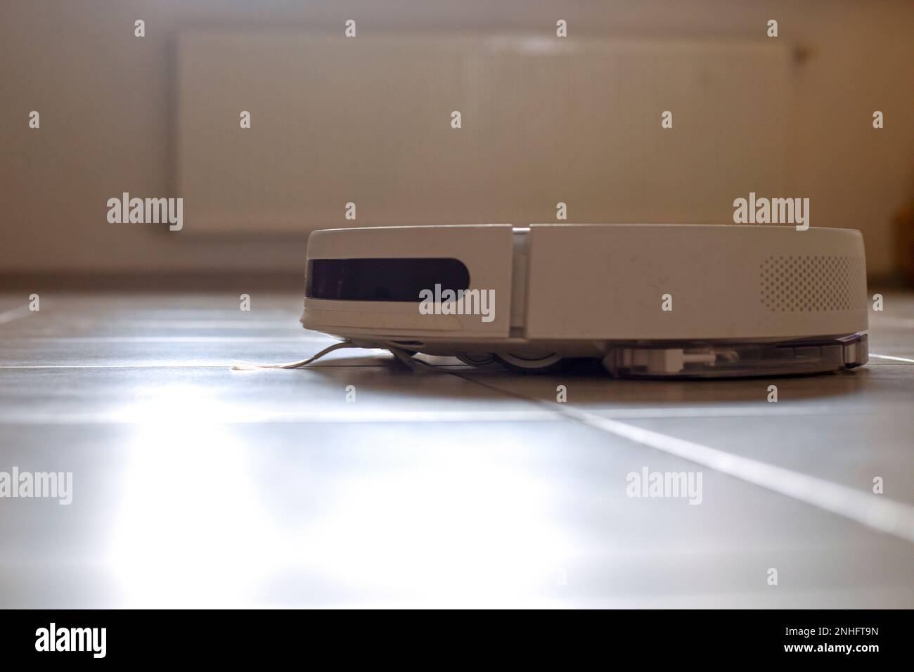 white robot vacuum cleaner cleans the room near the closed doors ...