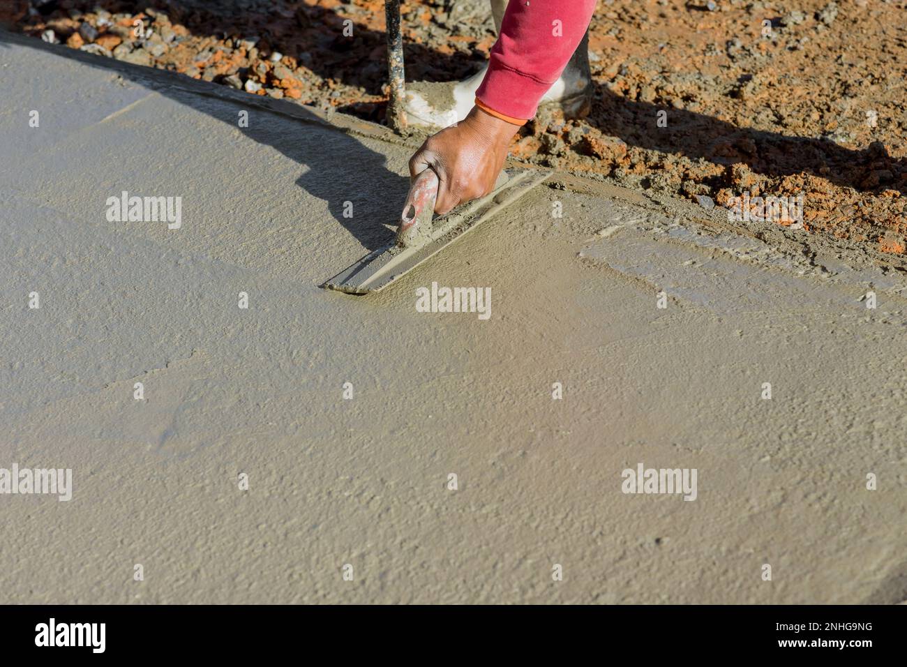 Worker plastering wet concrete cement floor using trowel after pouring ...