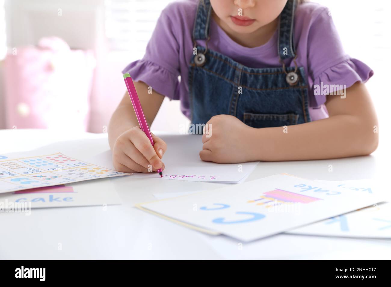 Little girl writing numbers in classroom at English lesson, closeup ...