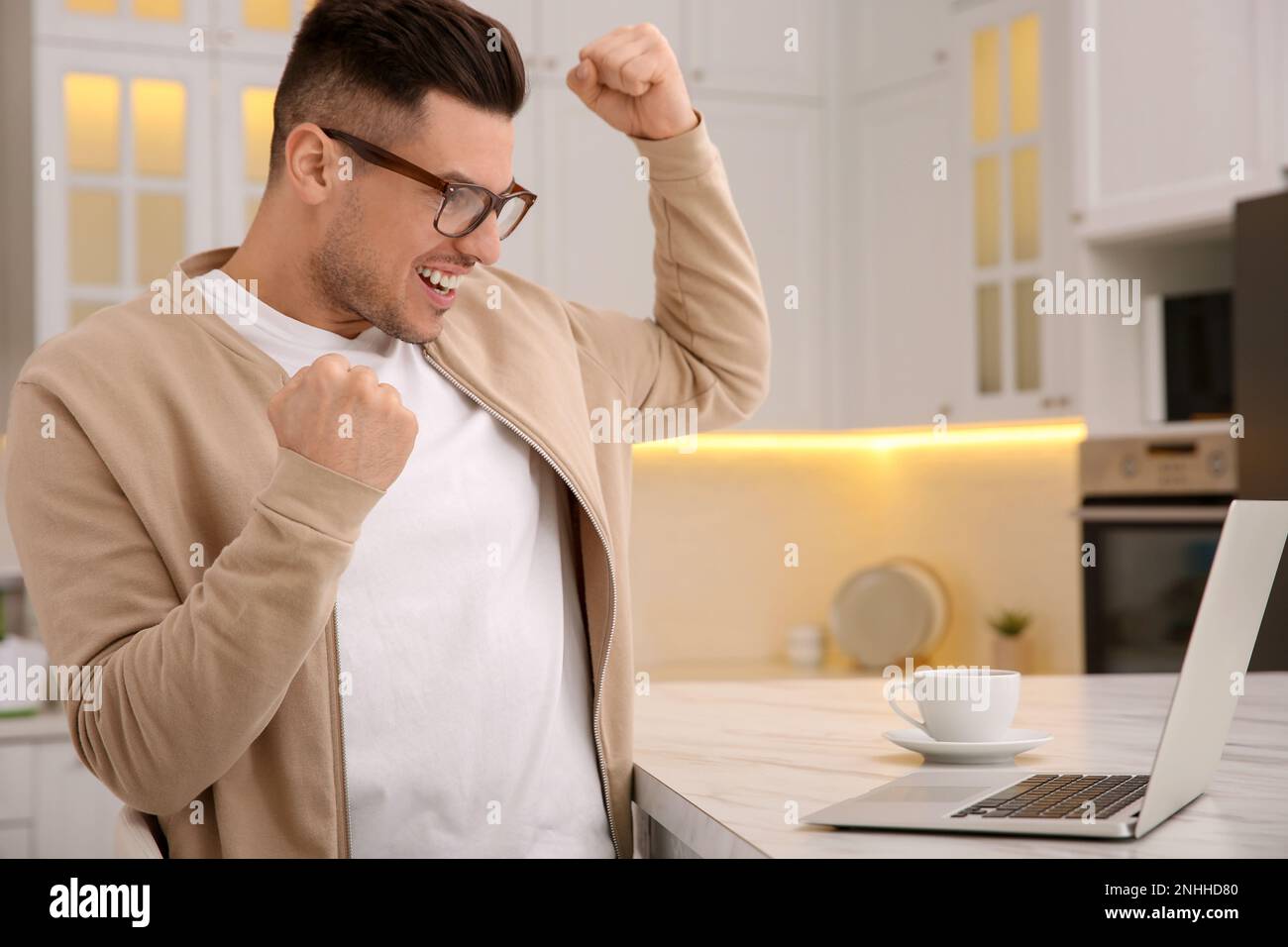 Emotional man participating in online auction using laptop at home ...