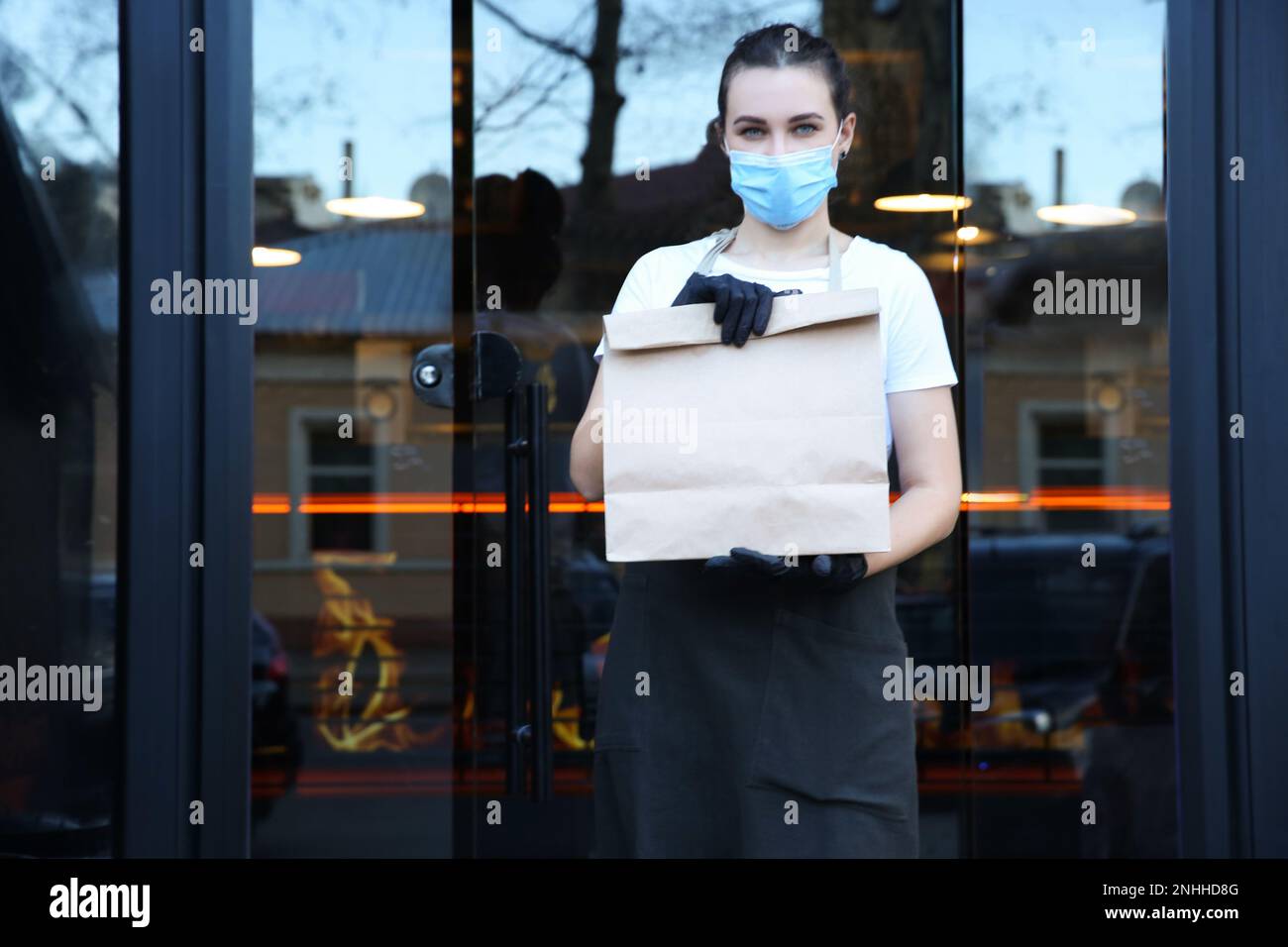 Waiter with packed takeout order near restaurant. Food delivery service ...