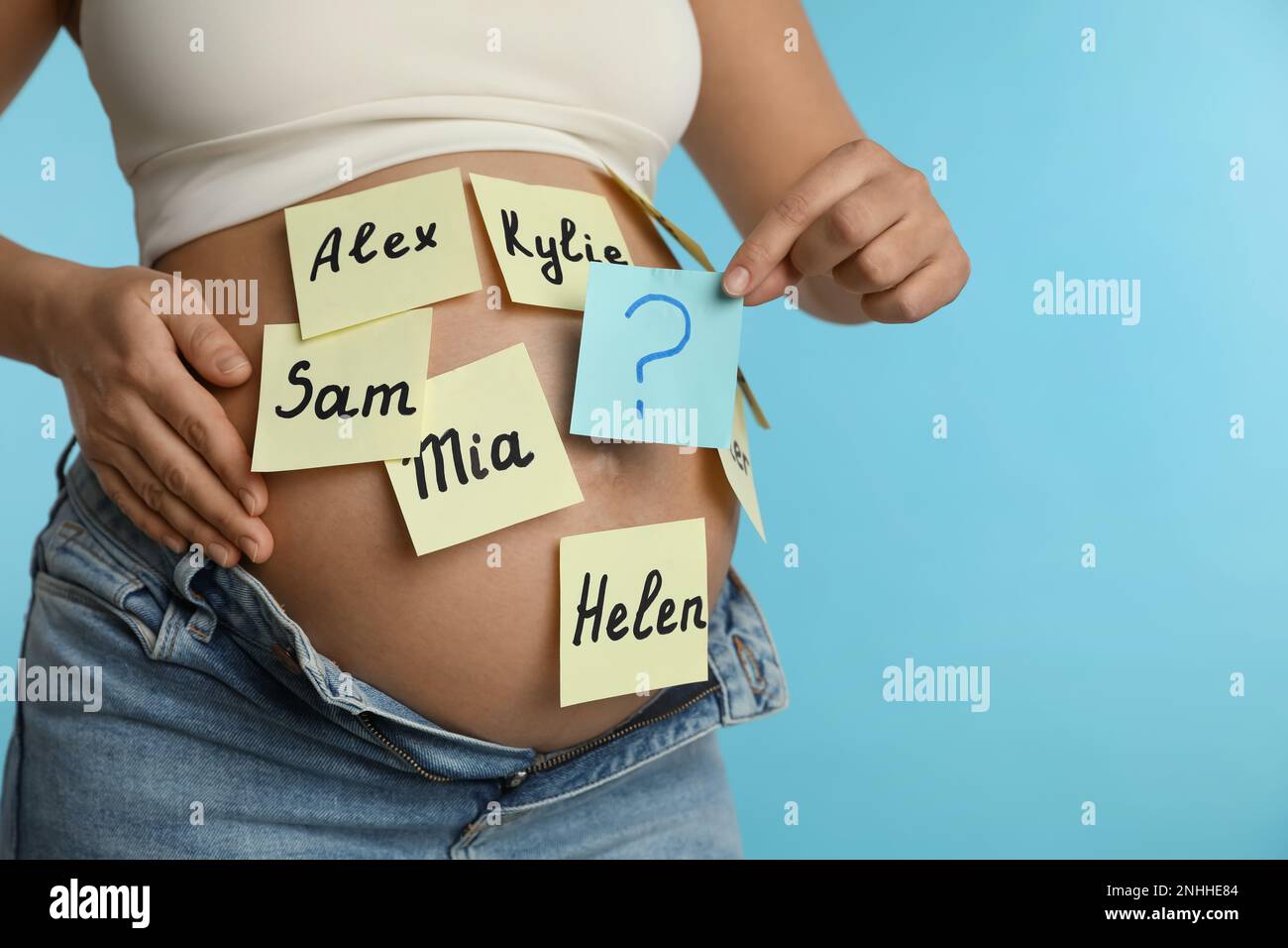 Pregnant woman with different baby names on belly against light blue ...