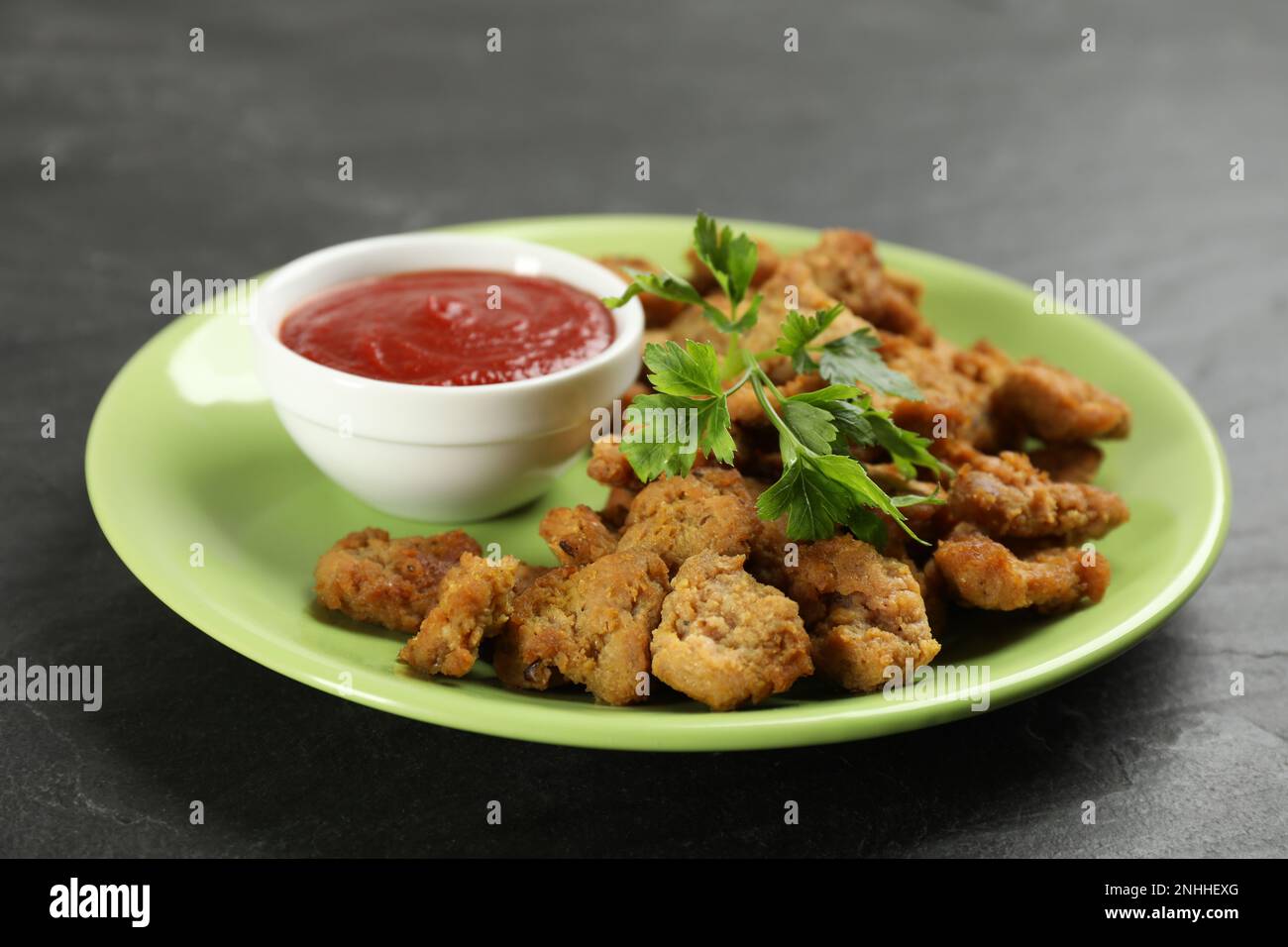 Delicious cooked soy meat chunks with sauce black slate table, closeup ...