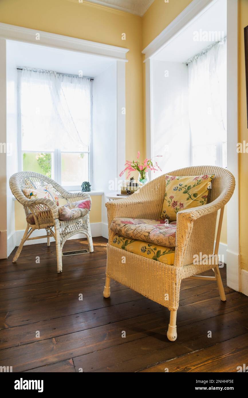 White wicker armchairs with flowery cushions and small round table in ...