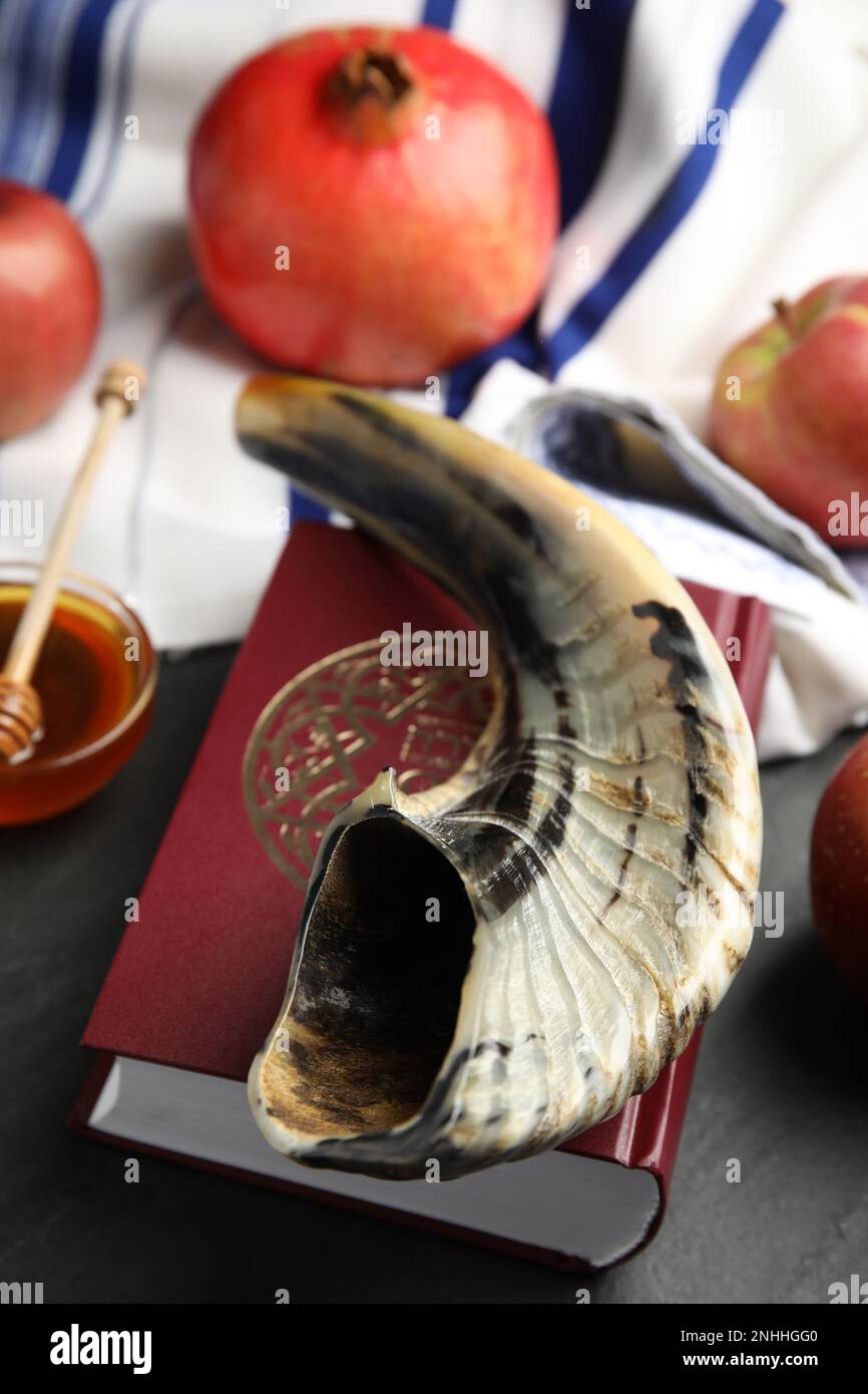 Shofar and book Torah with text in Hebrew on black table, closeup. Rosh ...