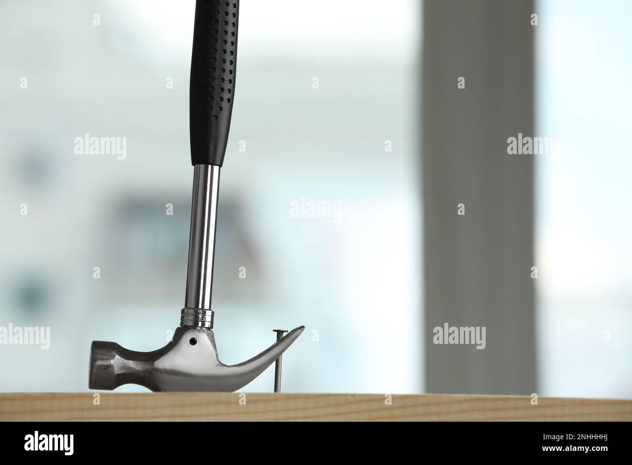 Hammer pulling metal nail out of wooden surface against blurred ...